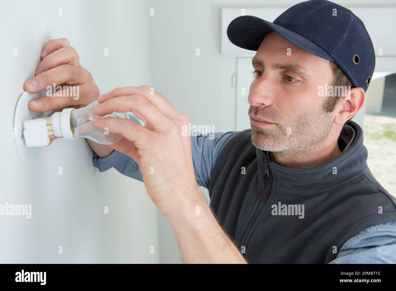 man fitting lightbulb to wall Stock Photo - Alamy