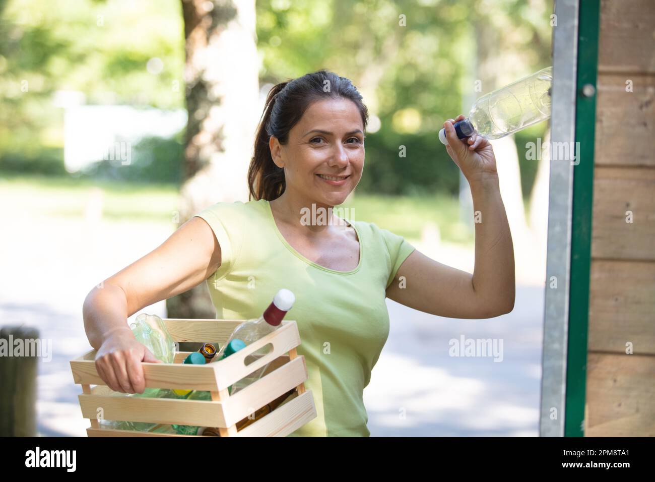 woman recycling glass bottles in a container Stock Photo - Alamy