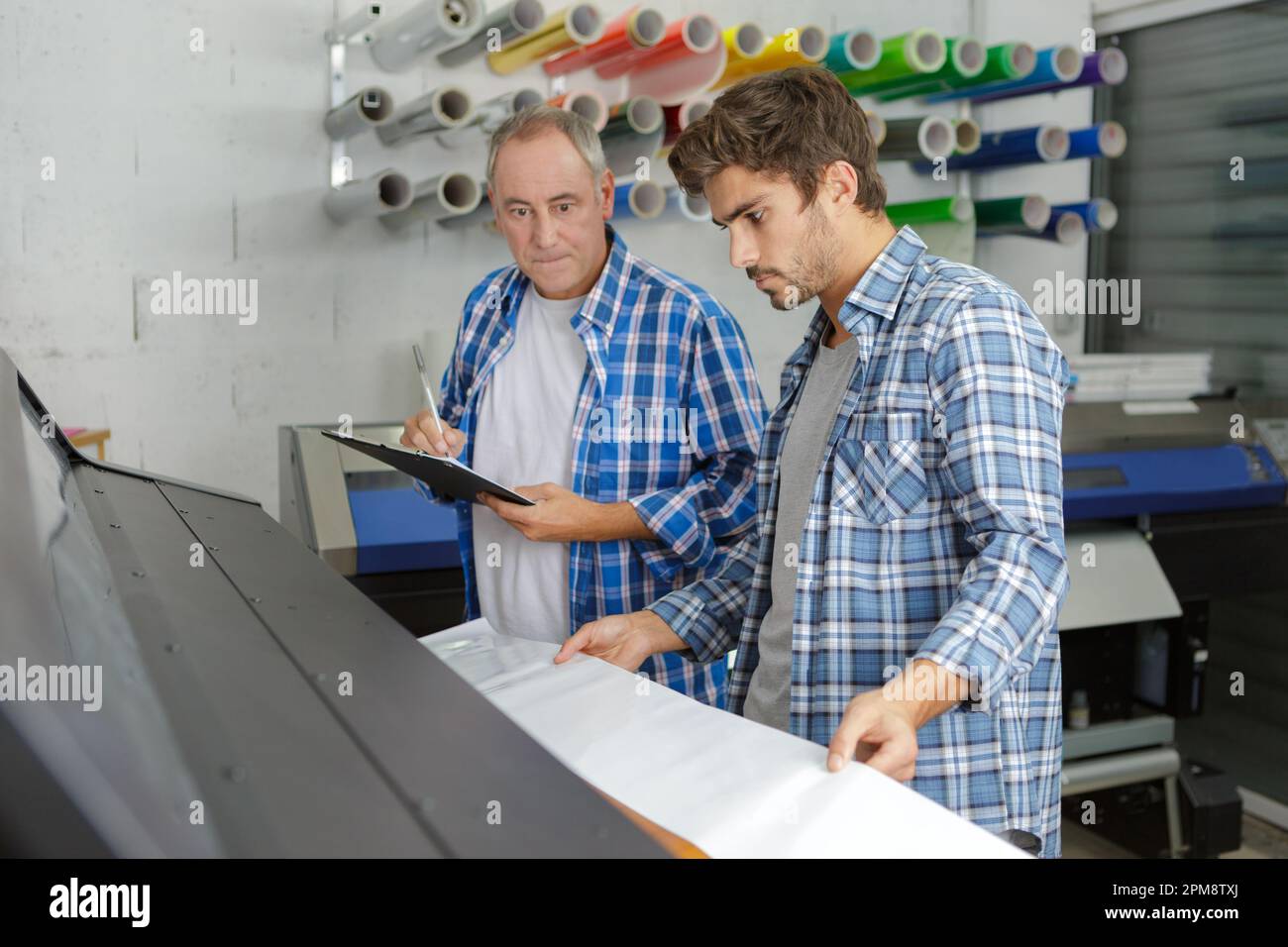 two men looking down at professional printer Stock Photo - Alamy