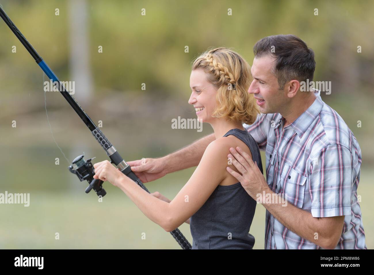 man helping his wife to fish Stock Photo - Alamy