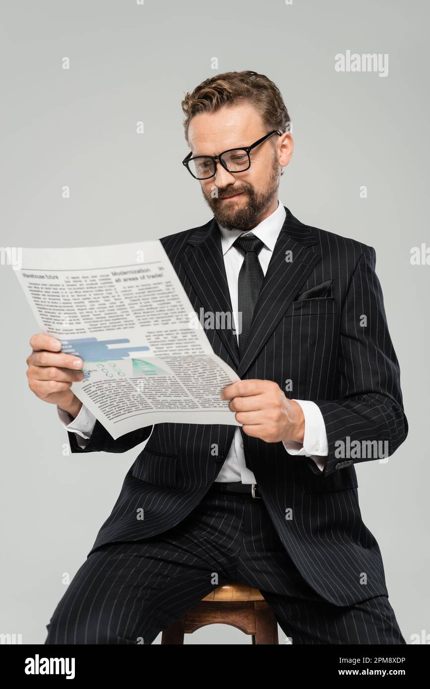 pleased businessman in suit and glasses reading newspaper isolated on ...
