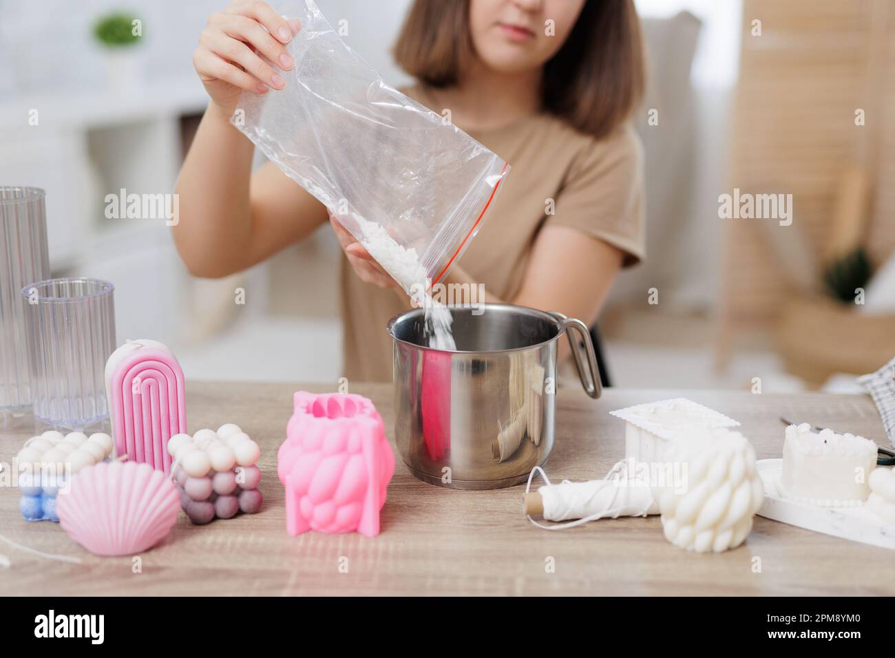 work and hobby concept - young woman making candles at home, pouring ...