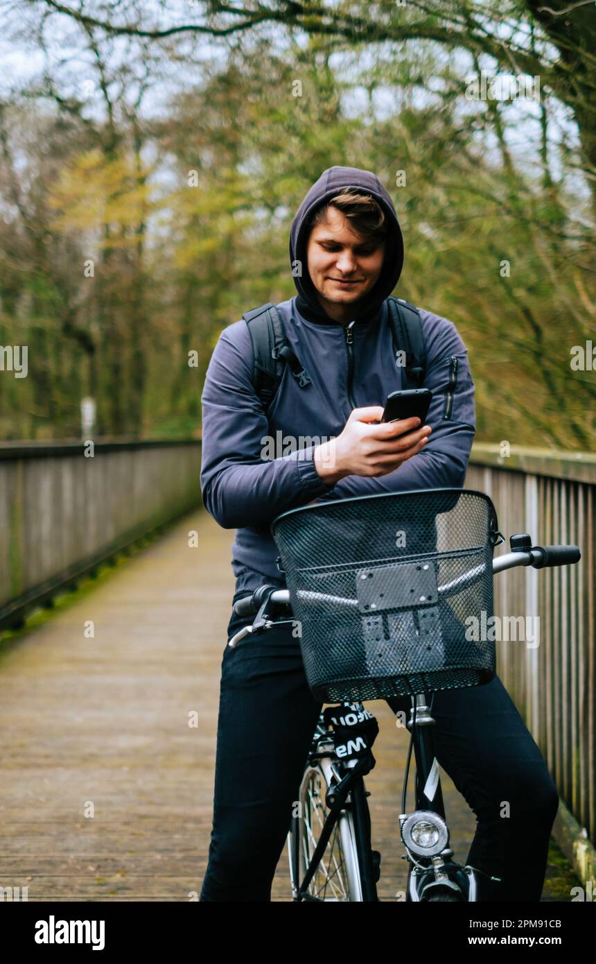 Young caucasian man cyclist ride on bicycle in the park and using ...
