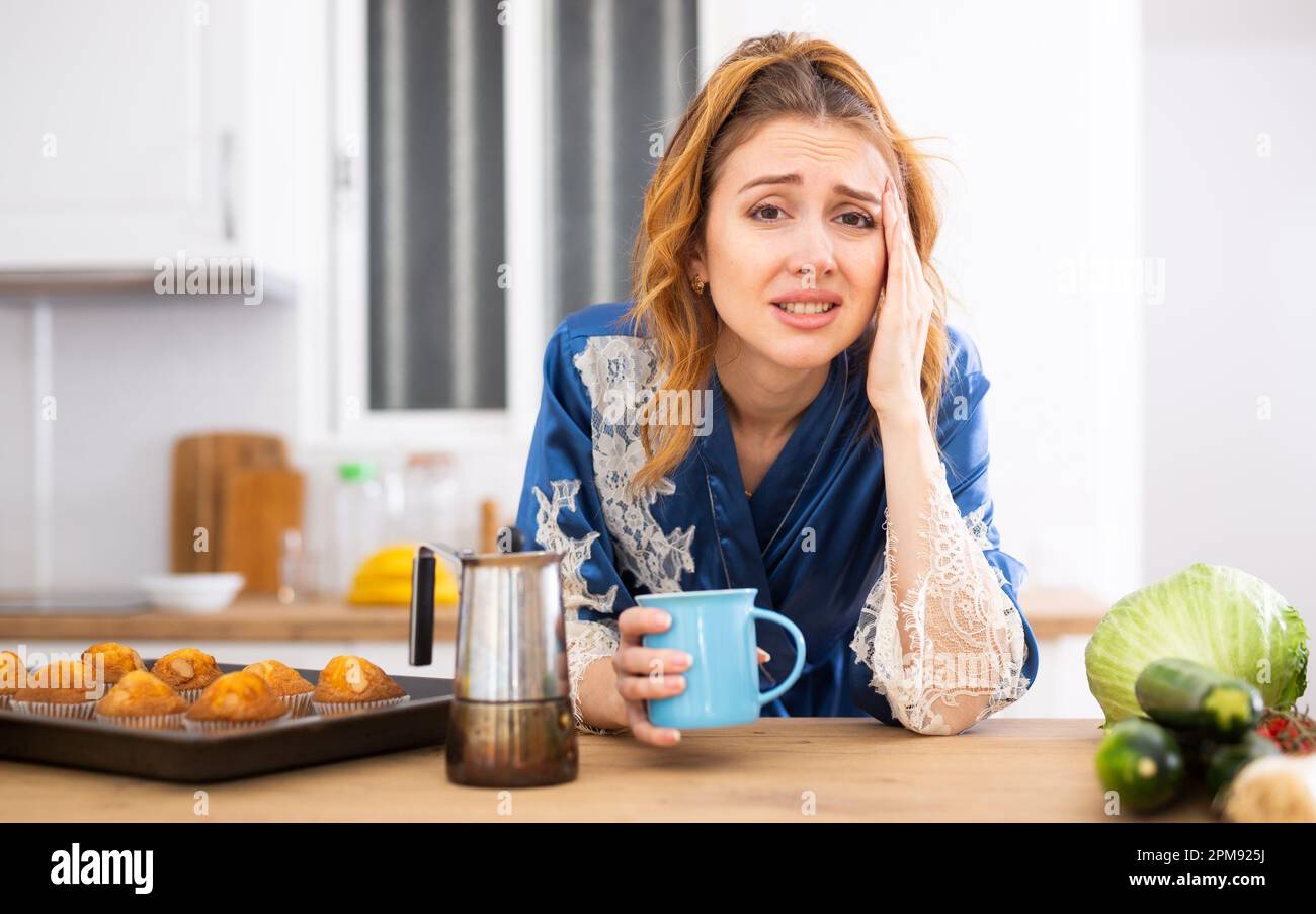 Exhausted woman drinking coffee at home Stock Photo - Alamy