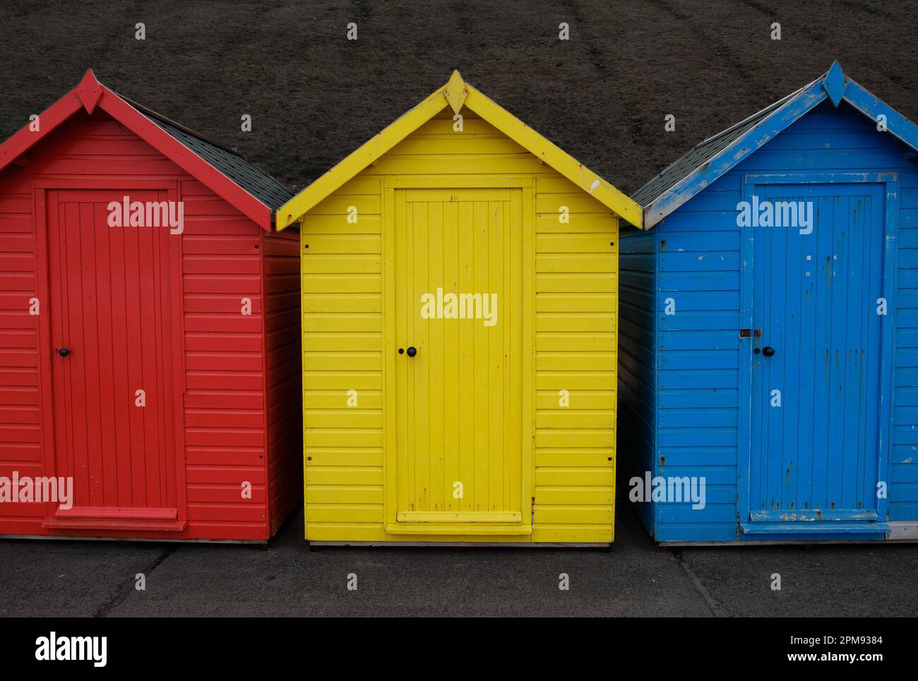 3 beach huts on Whitby promenade - red, yellow and blue Stock Photo - Alamy