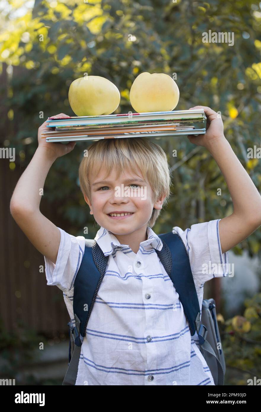 cute cheerful 6 year old boy holding stack of books and two big apples ...