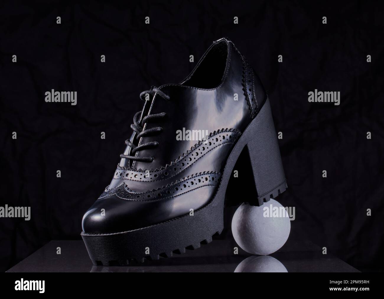 Women's black heeled shoe shot on a black background with a black ...