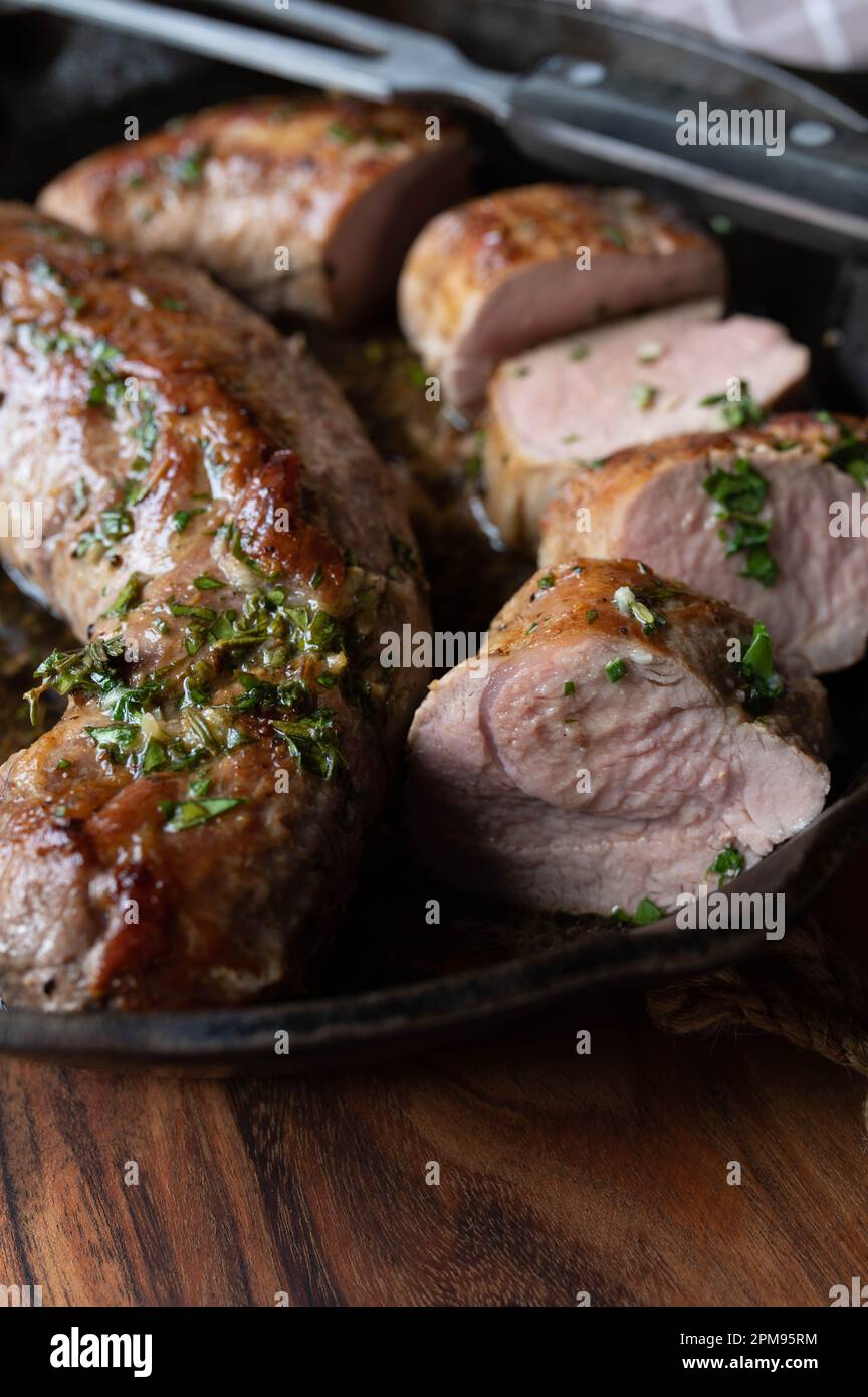 Pan fried medium pork fillet with melted herb butter in a cast iron pan ...
