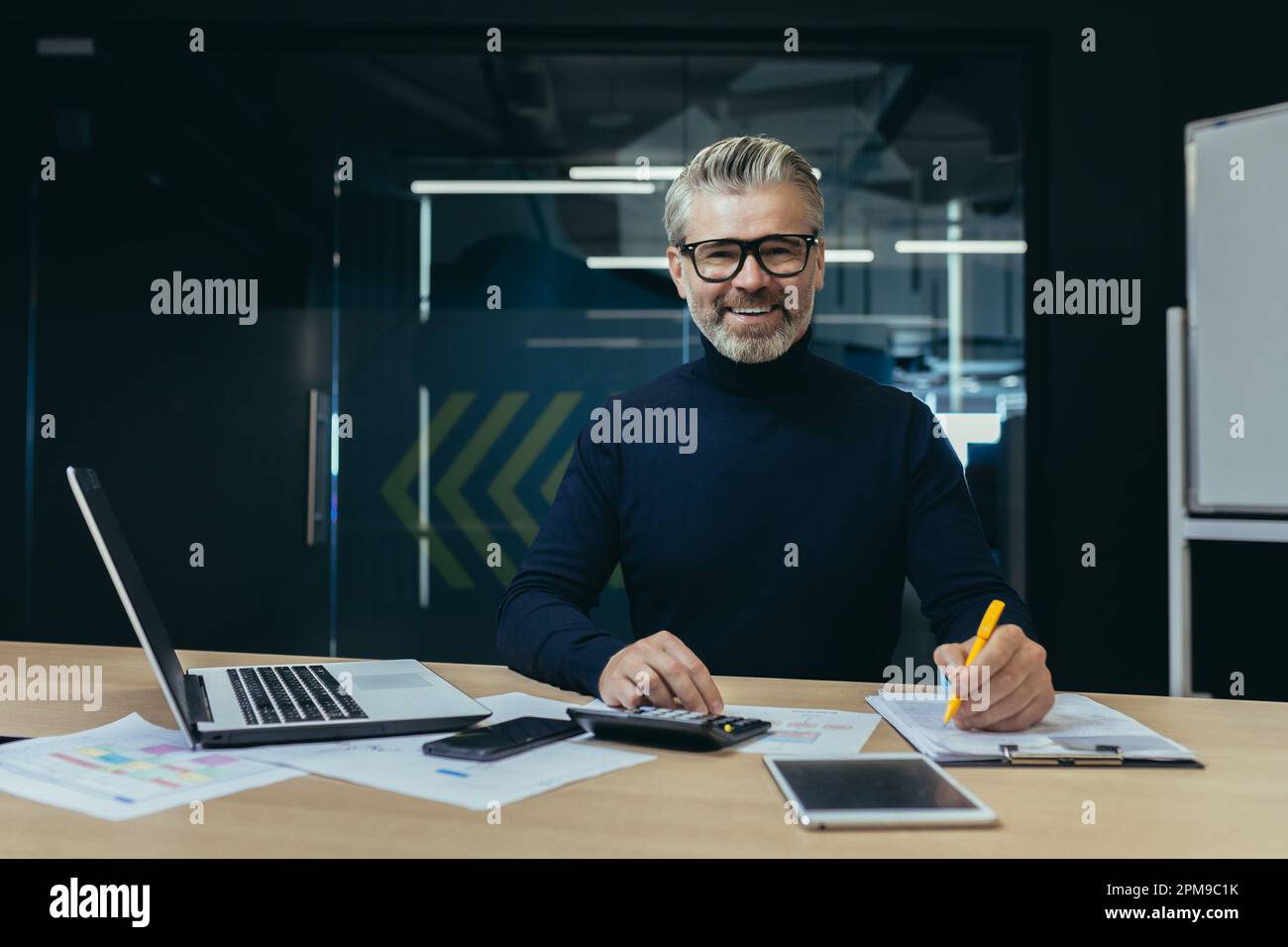 Portrait of an older gray-haired man, an accountant, an auditor sitting ...