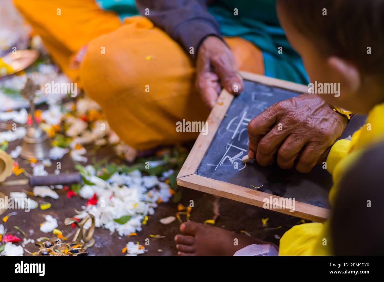 Priest is teaching young child to write Hindi letters with chalk and ...