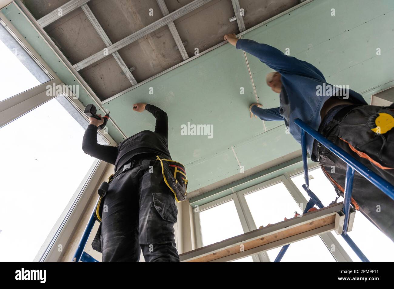 Workers fitting panel into frame of ceiling Stock Photo - Alamy