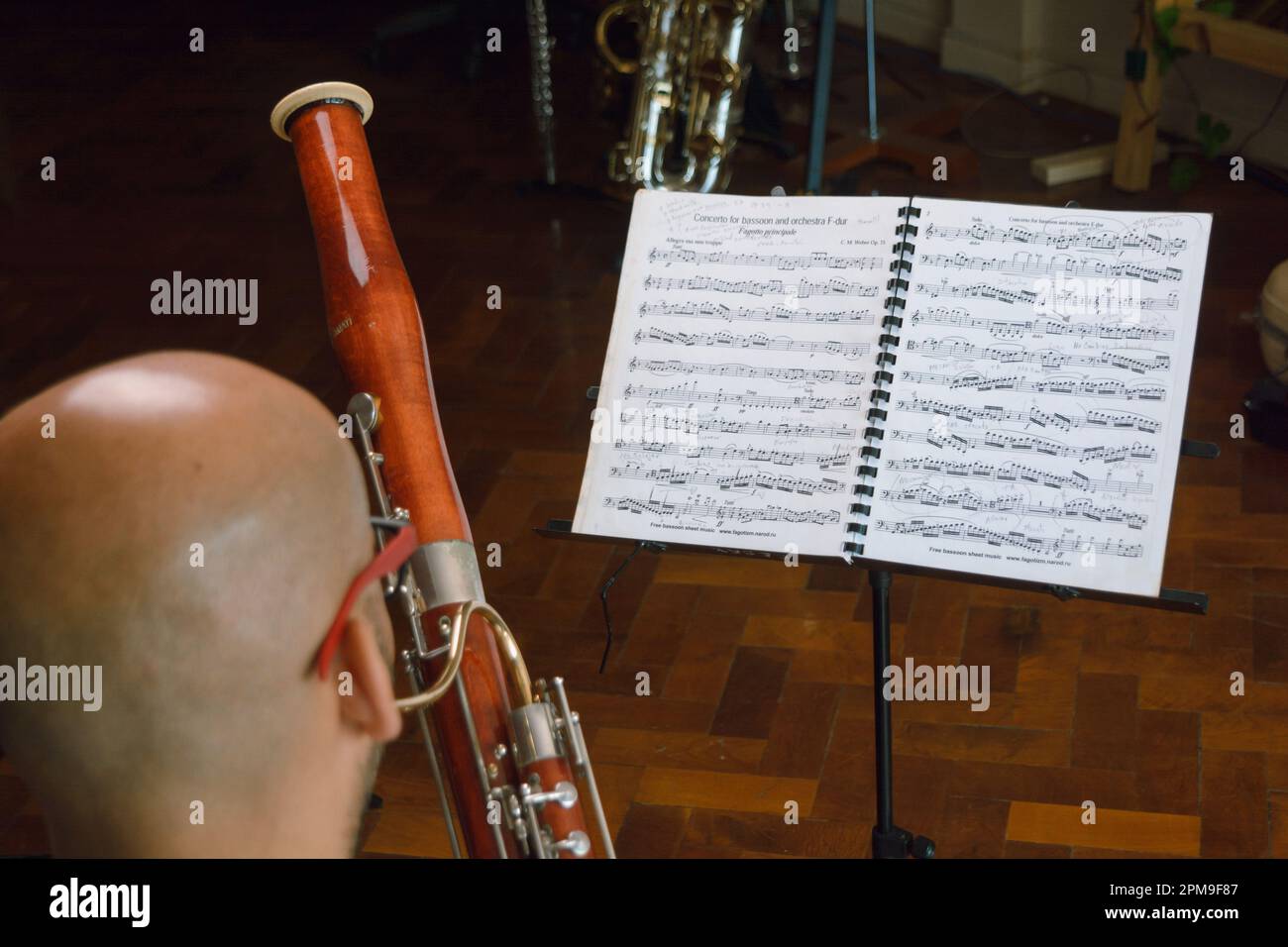 rear view of bald man sitting at home playing bassoon, reading sheet ...