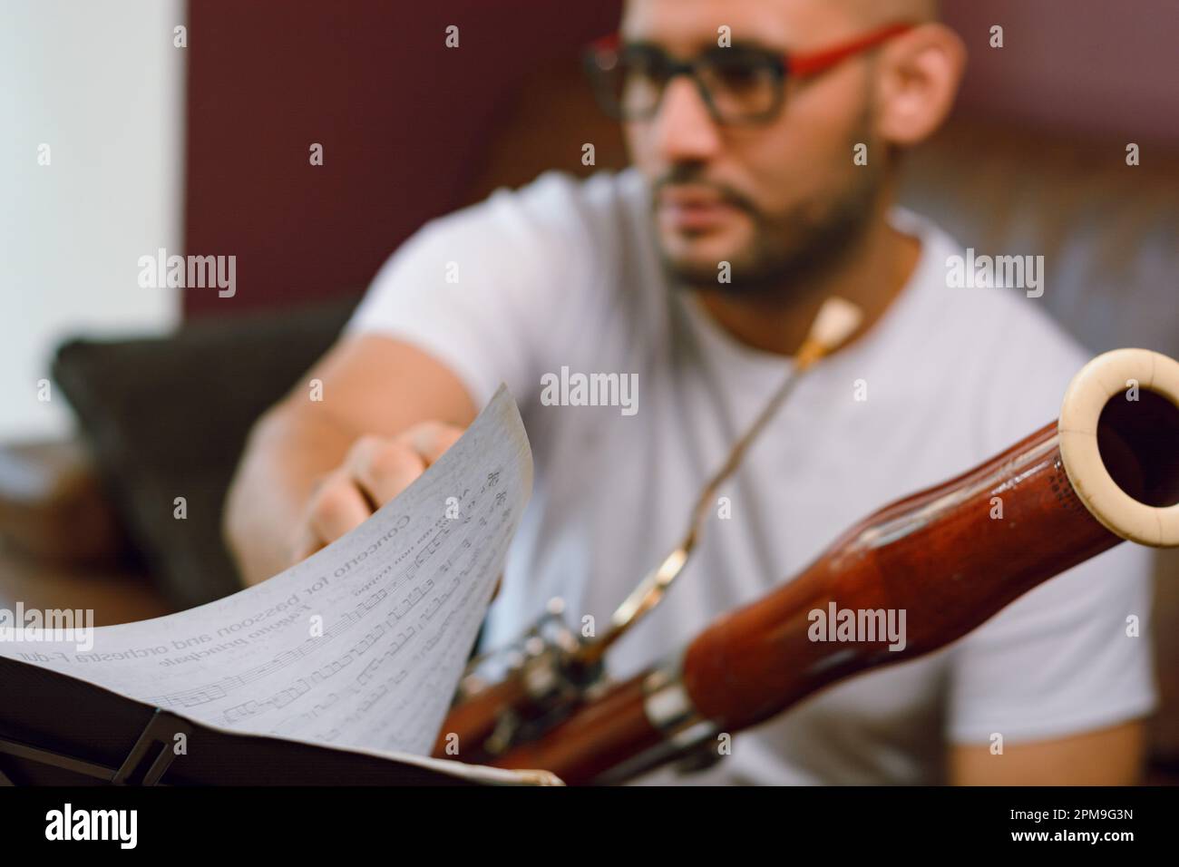 blurred young man sitting at home with a bassoon turning the sheet ...