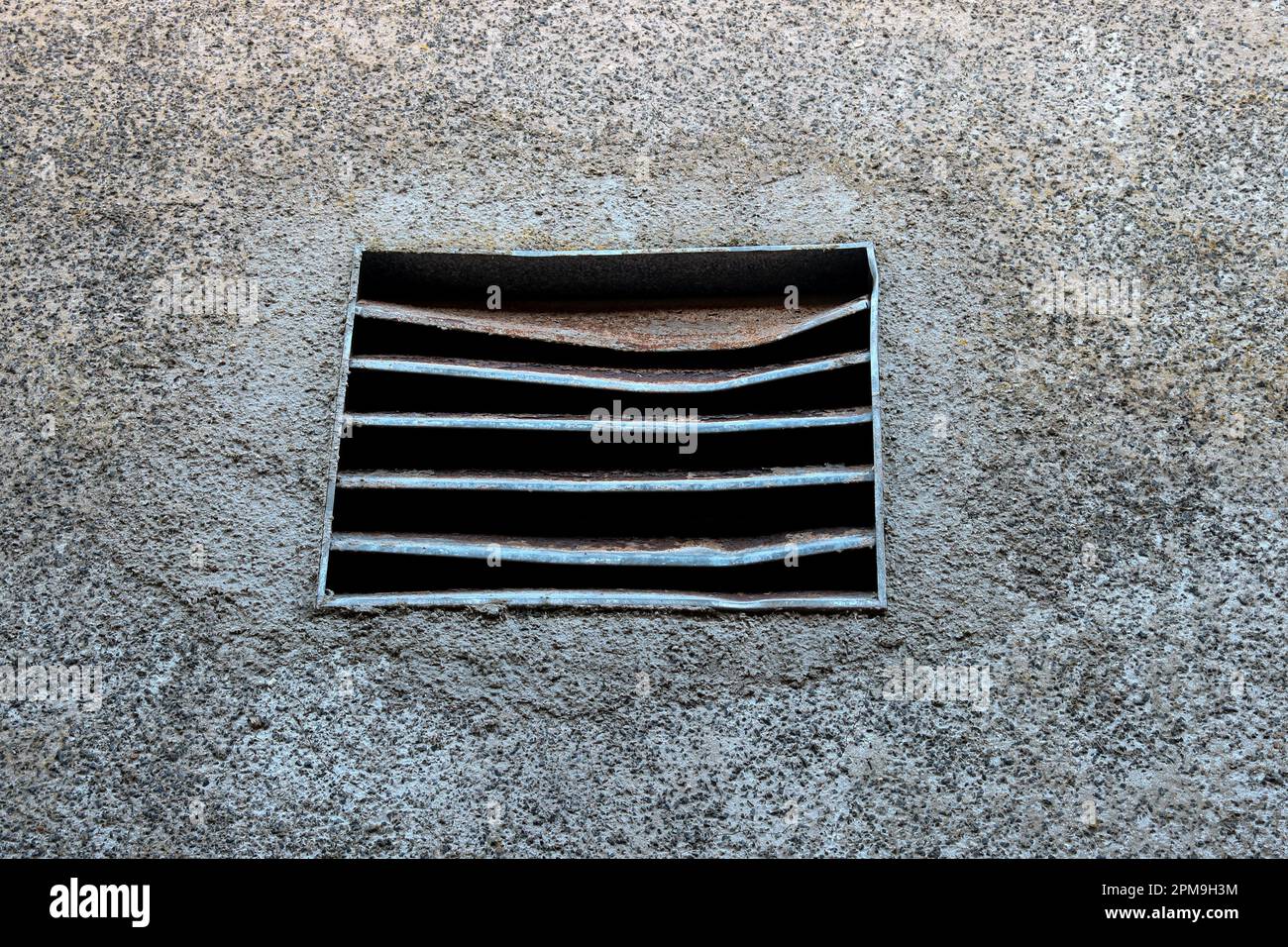 Old bent and damaged air vent duct in an old roughcast building wall ...