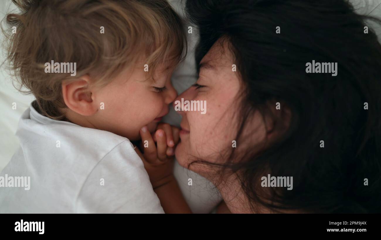 Mother and child love and care laying in bed. Lifestyle moment of mom and son eskimo kiss during ...