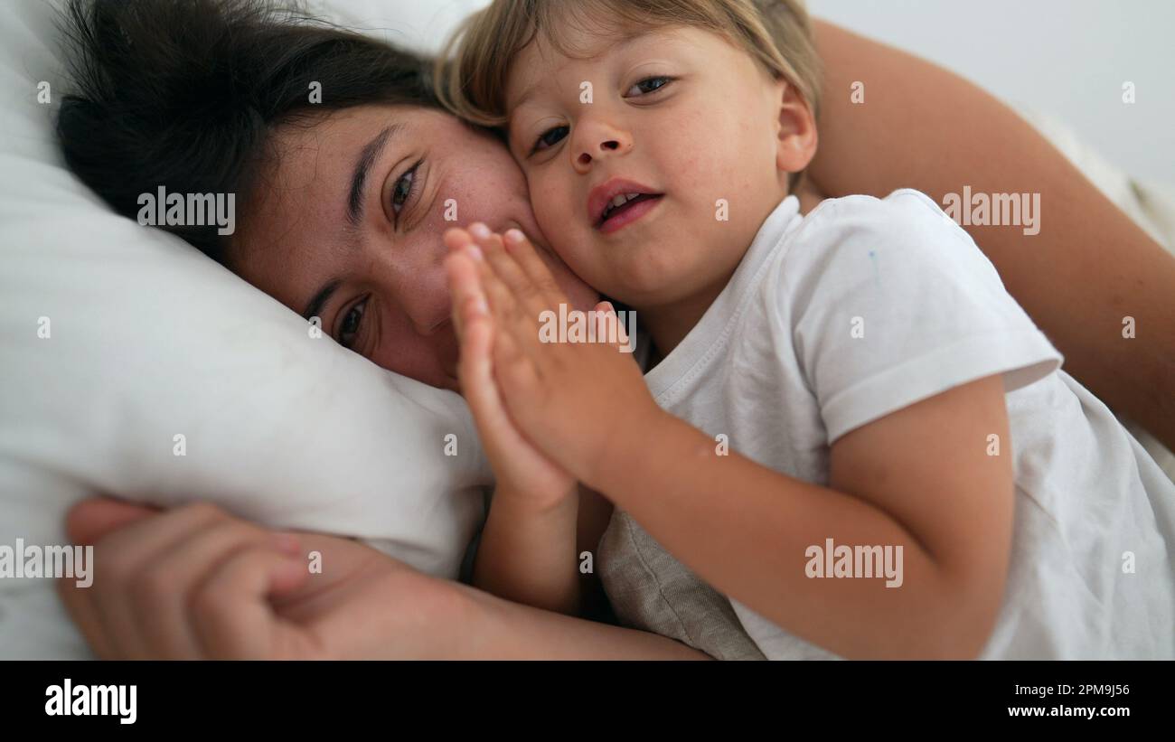 Mother and child son laying in bed together in authentic real life ...