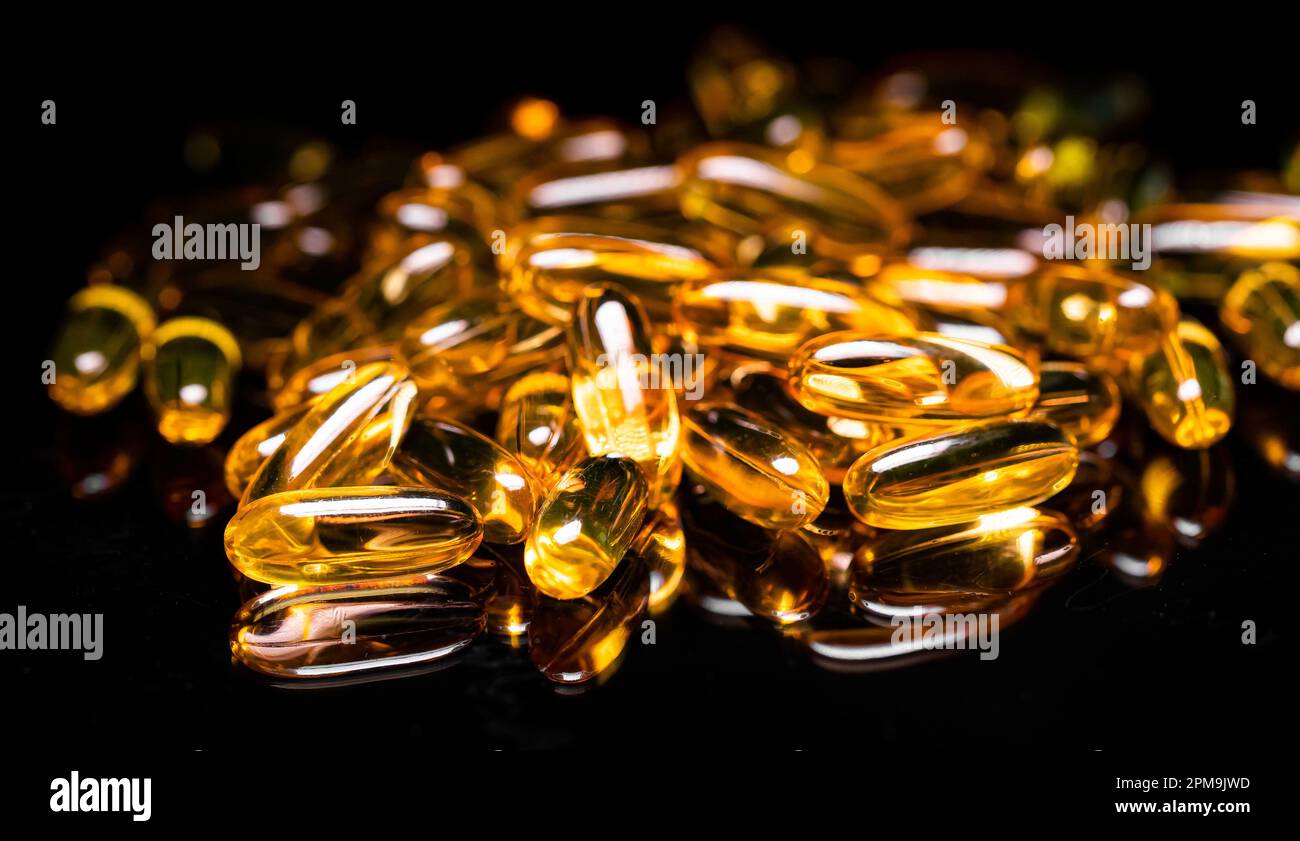 Macro Close up of Omega 3 gel capsule on a reflective black background ...