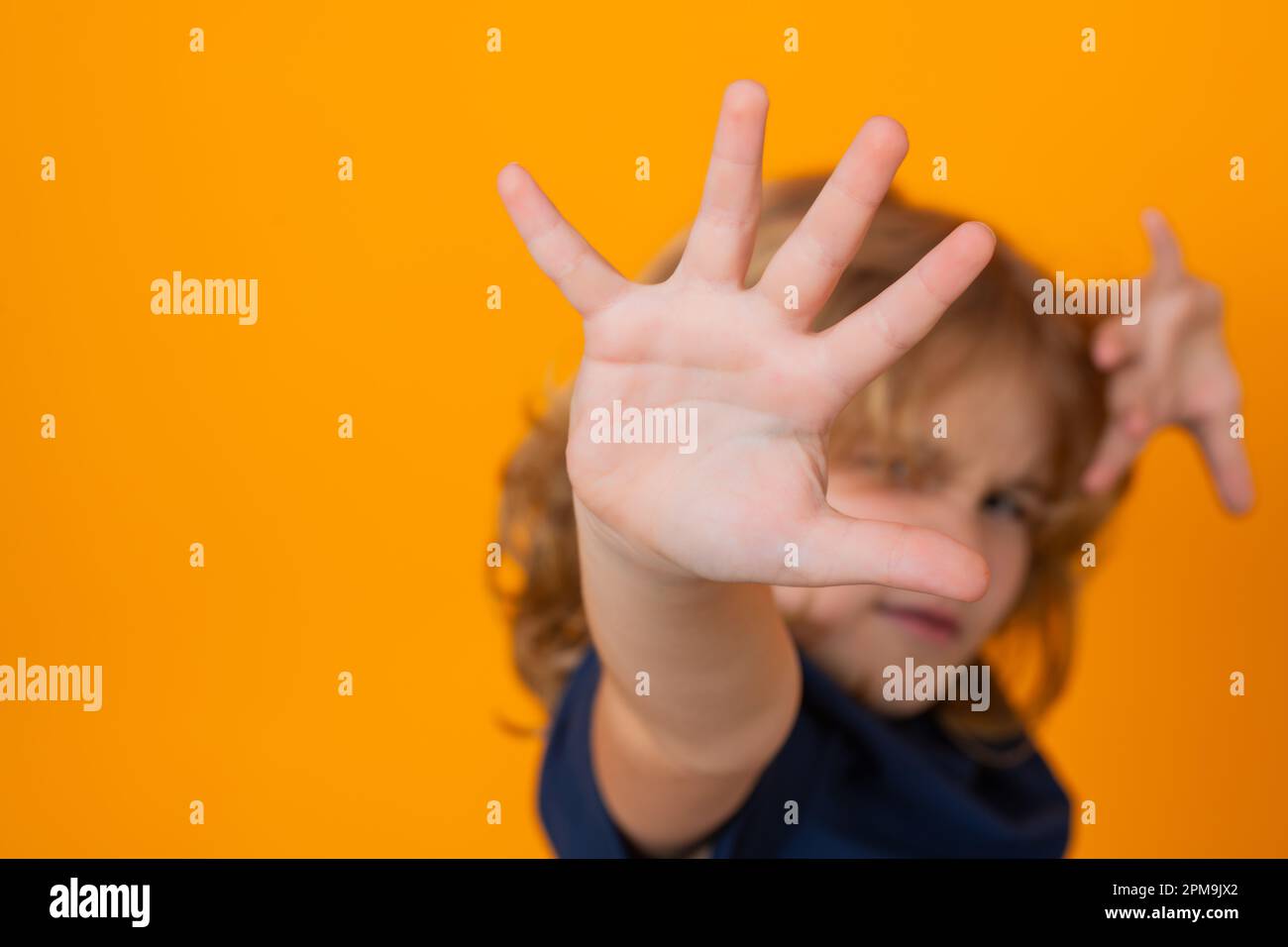 Child making stop gesture on yellow isolated studio background. Kid ...