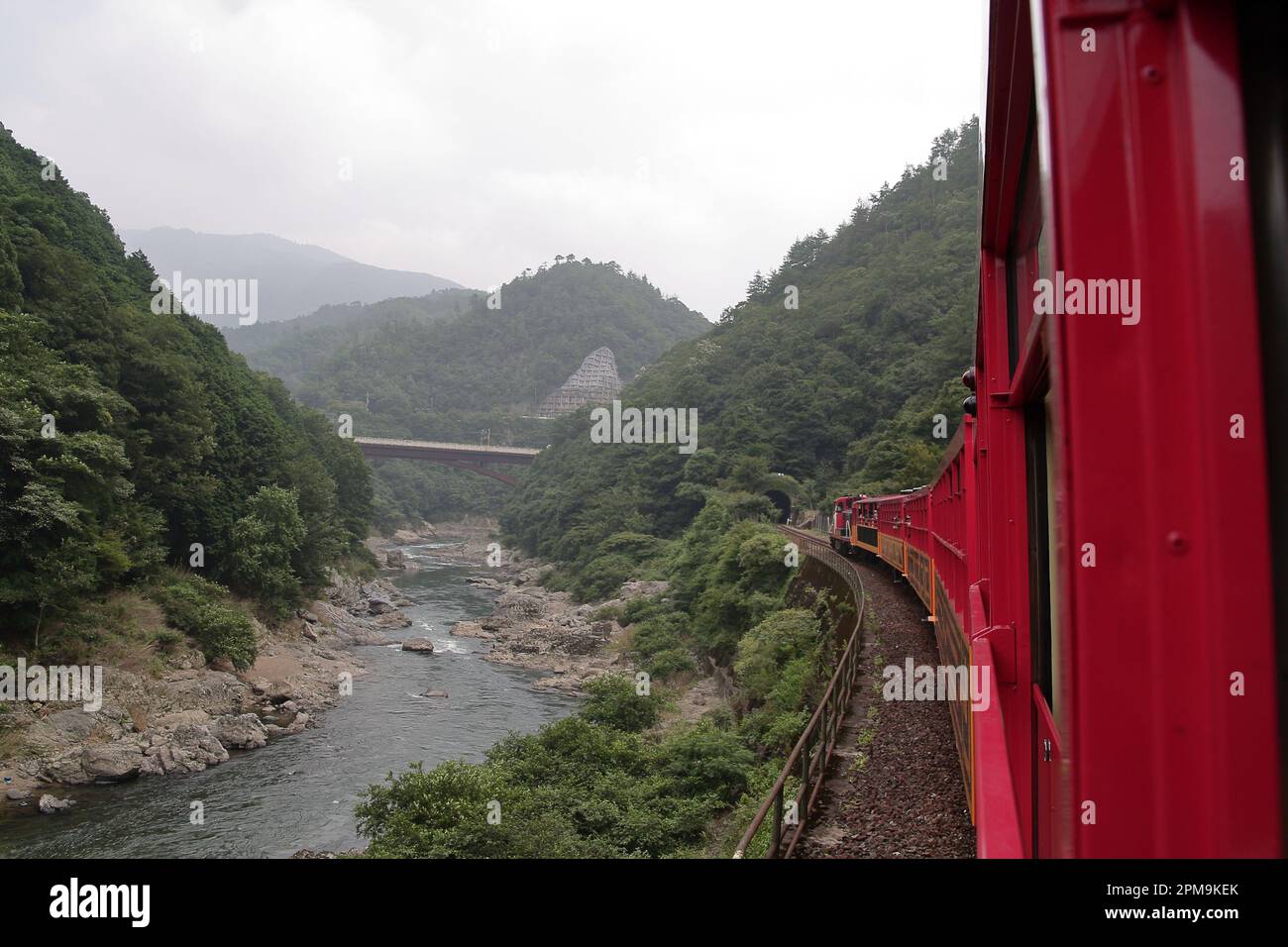 a train moving by a river through the mountains in summer, blurred ...
