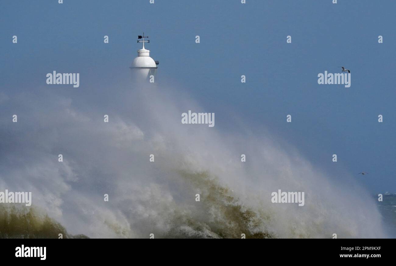 Waves crash around the lighthouse on the harbour arm in Folkestone ...