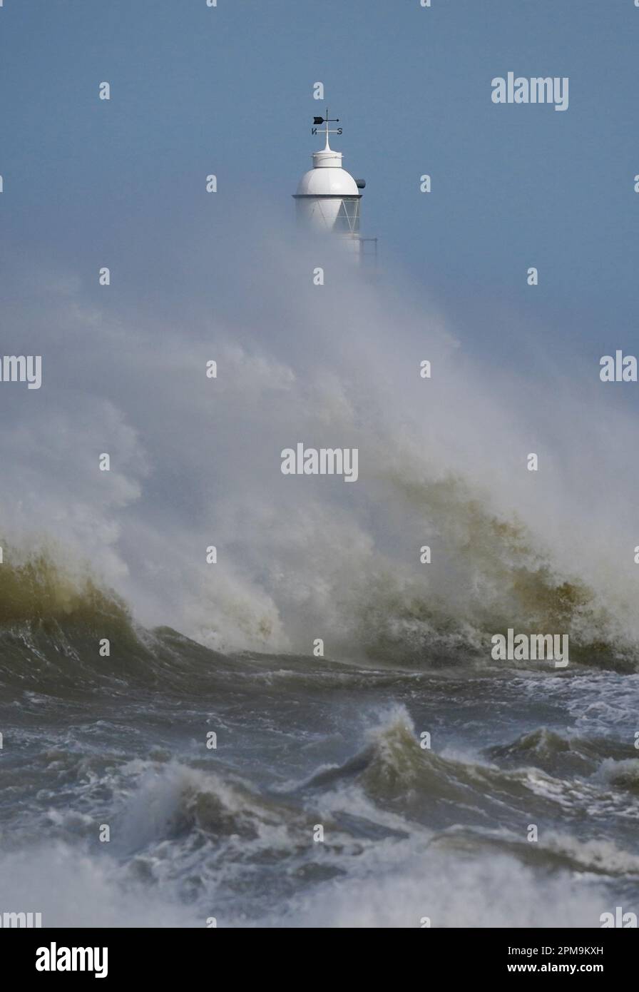 Waves crash around the lighthouse on the harbour arm in Folkestone ...