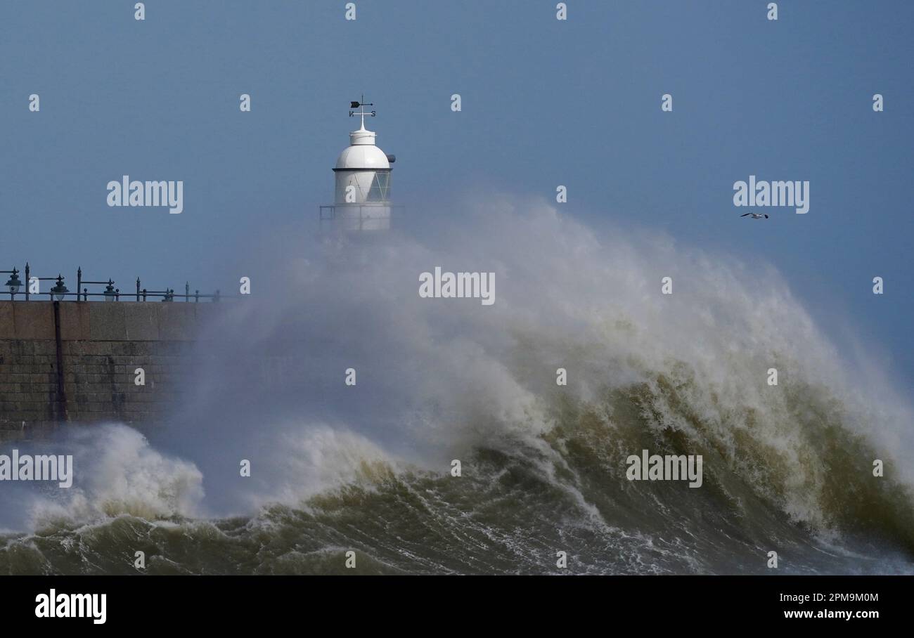 Waves crash around the lighthouse on the harbour arm in Folkestone ...