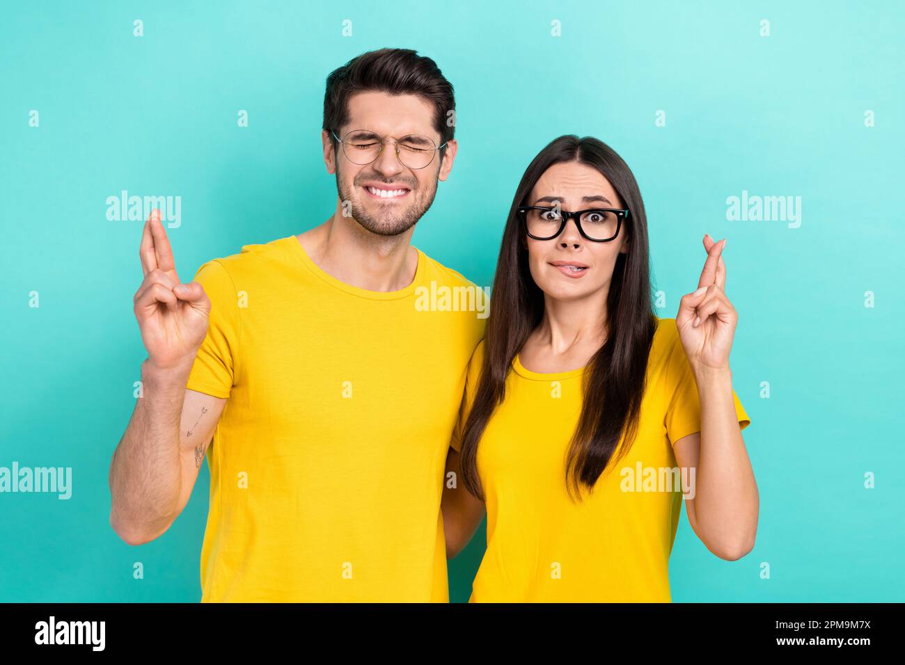 Photo of two young nervous people panic crossed fingers wait bite lips ...