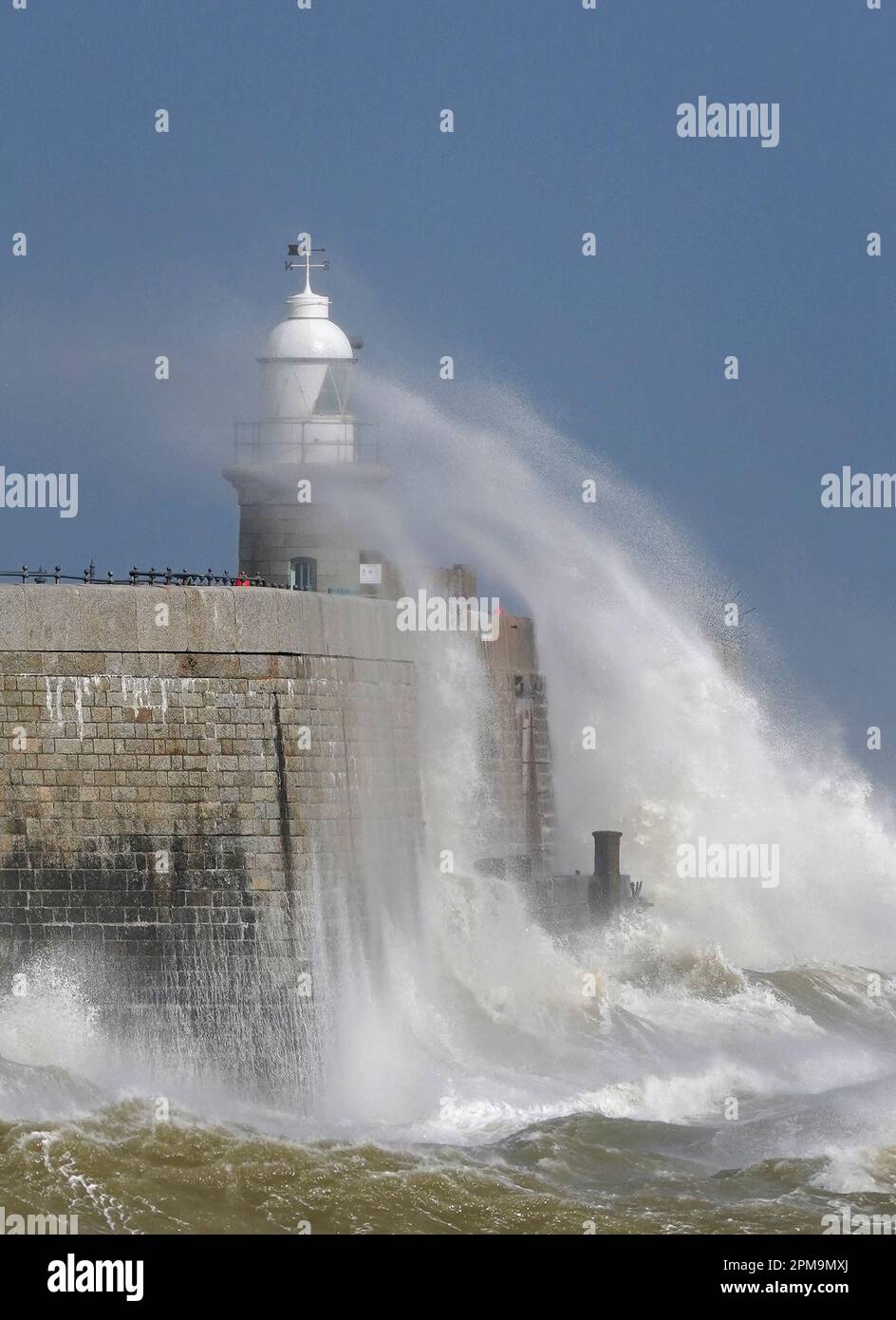 Waves crash around the lighthouse on the harbour arm in Folkestone ...