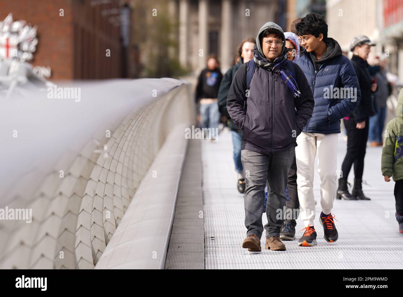 People walk across Millennium Bridge, London, as strong winds sweep ...