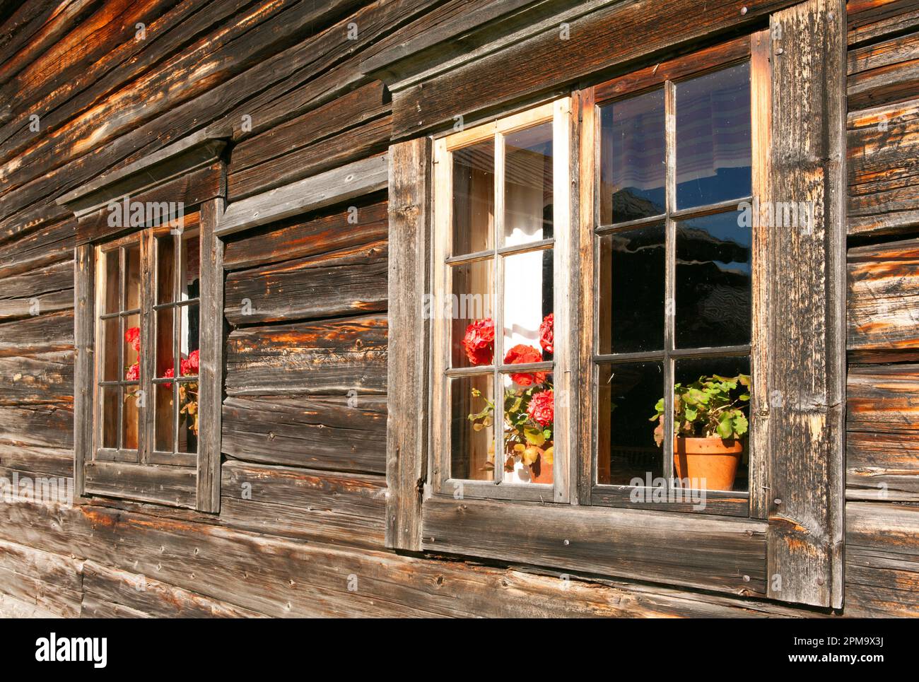 Wooden walls and windows at an ancient building. Flower, flower-pot ...
