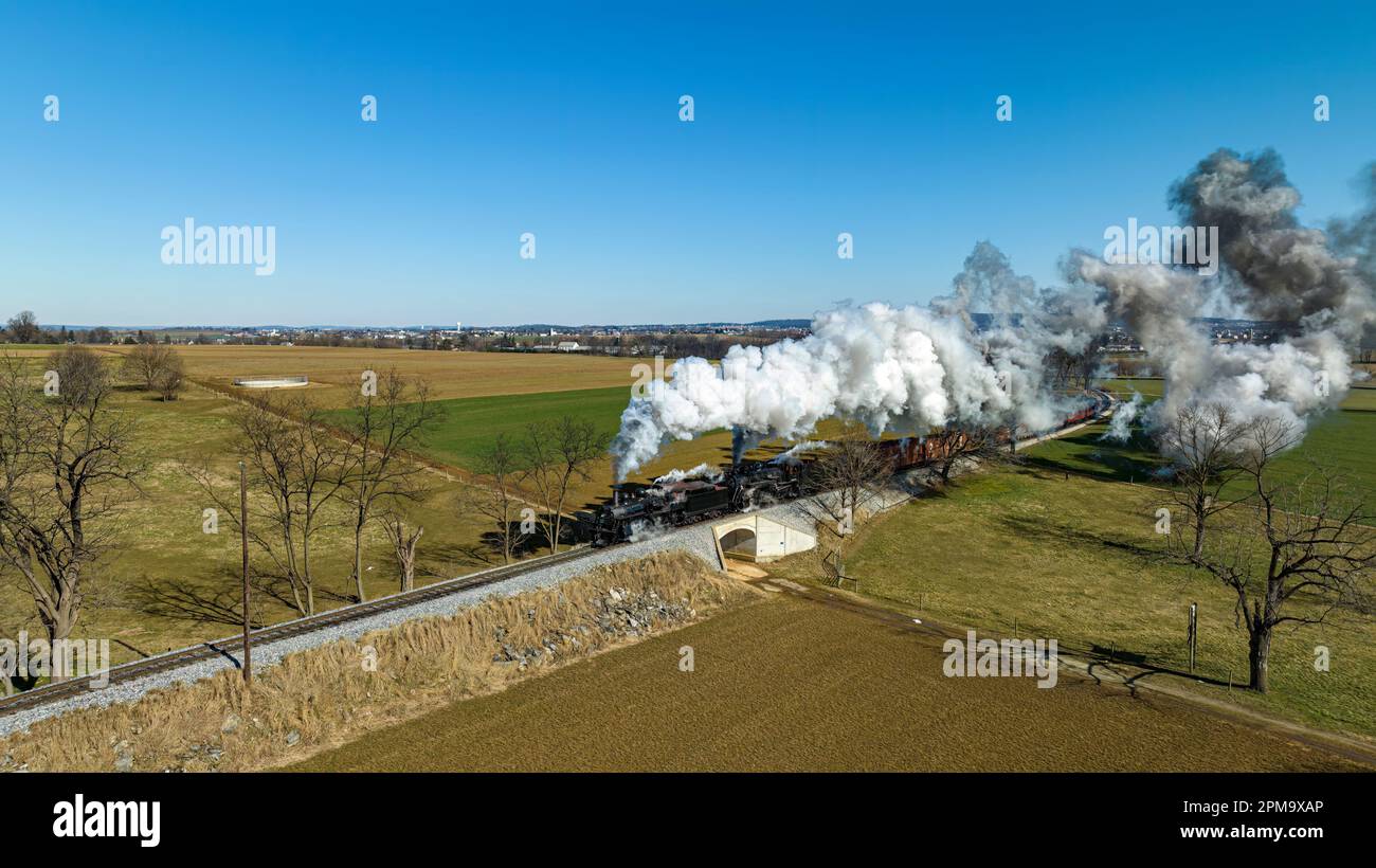 an old-fashioned steam engine train emerging from a set of train tracks ...