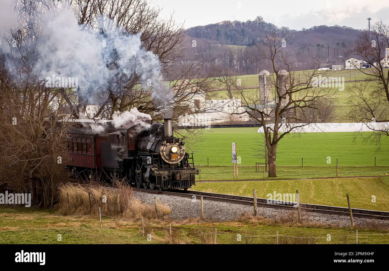 A vintage steam locomotive engine is pictured traveling through a lush ...