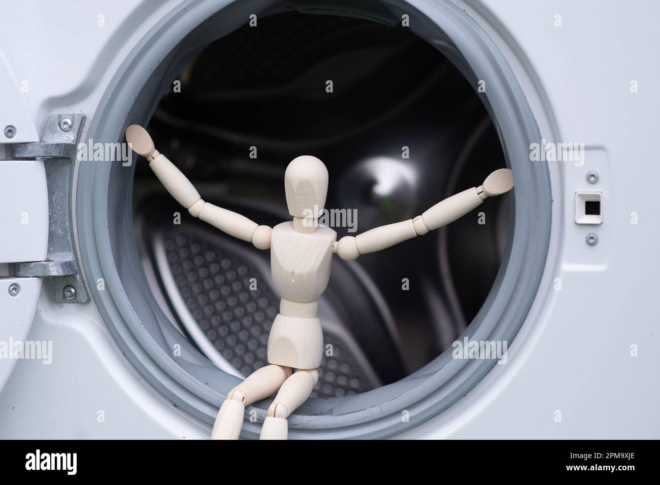 washing machine repair concept. A figurine of a man sits in the open ...