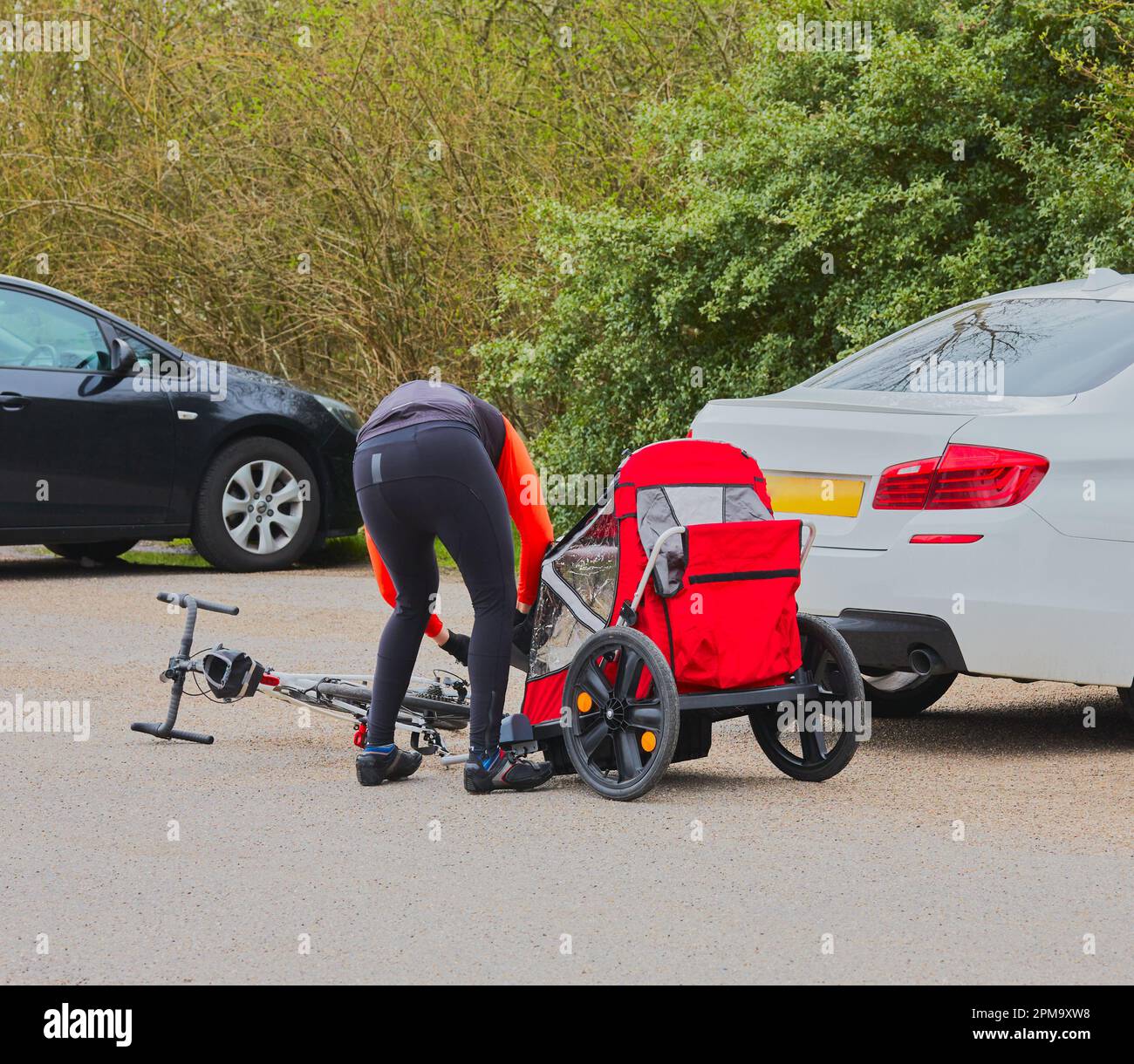 Man with bicycle and child carriage in a car park ready to go on a bike ...