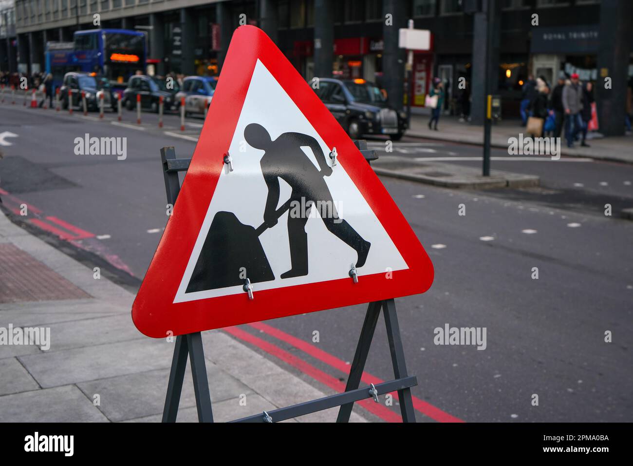 Red triangle warning roadworks sign placed at pavement, blurred city ...