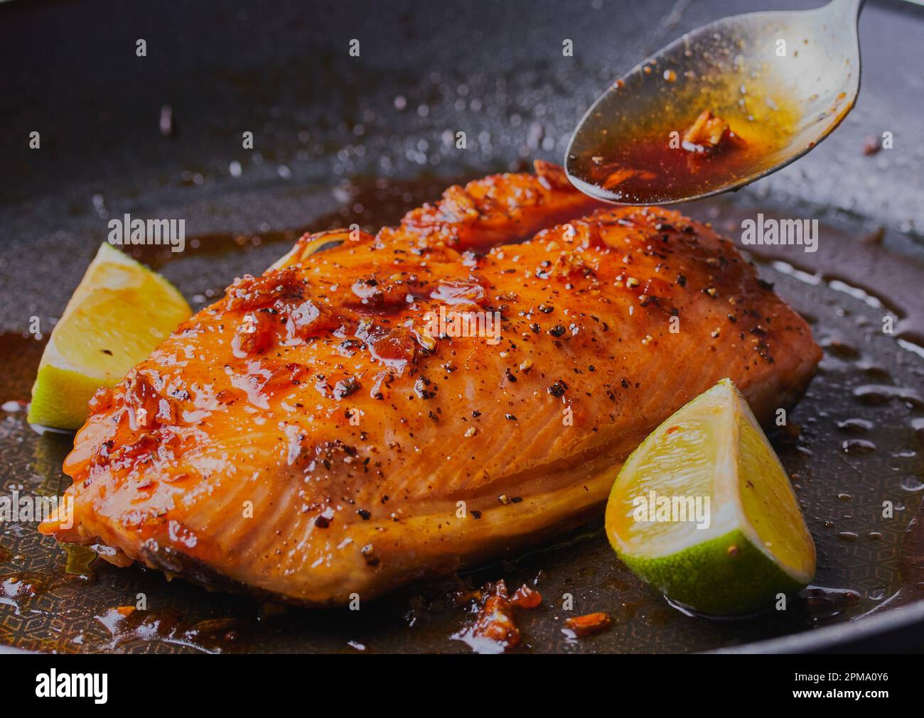 Pan fried salmon fillet with honey,garlic,spices and lime juice being ...