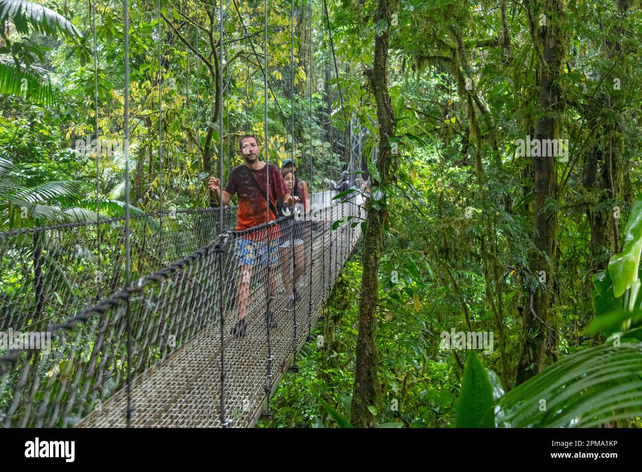 La Fortuna, Costa Rica - Tourists cross a suspension bridge in the rain ...