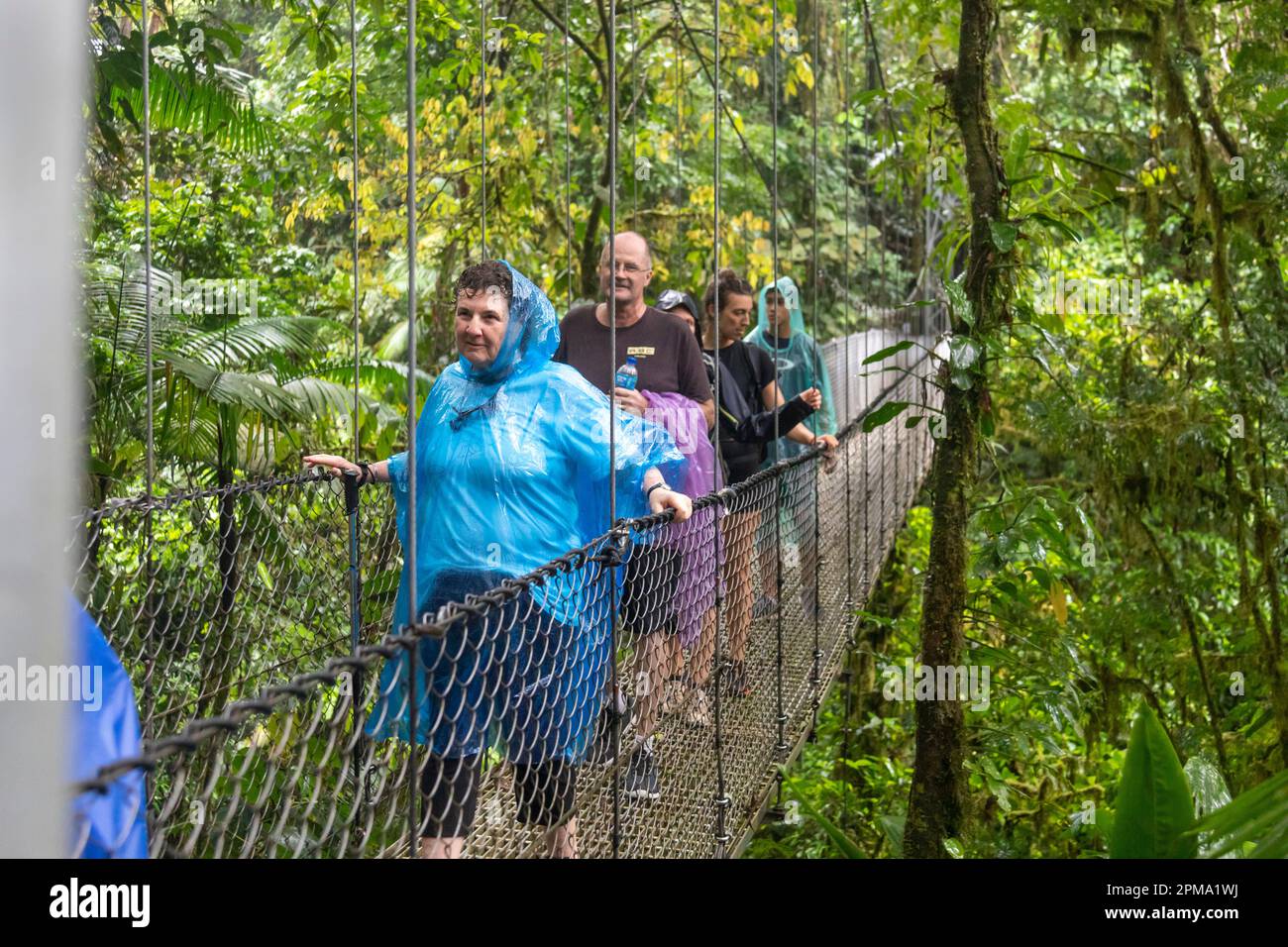 La Fortuna, Costa Rica - Tourists cross a suspension bridge in the rain ...
