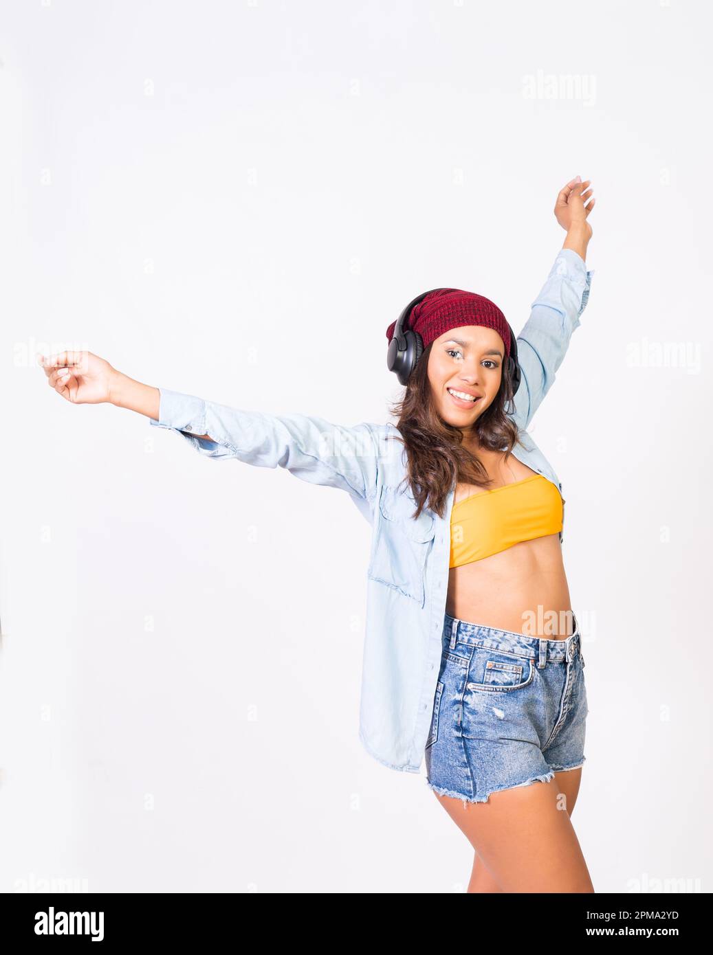 A smiling young Latina woman wearing a colorful dress and headphones ...