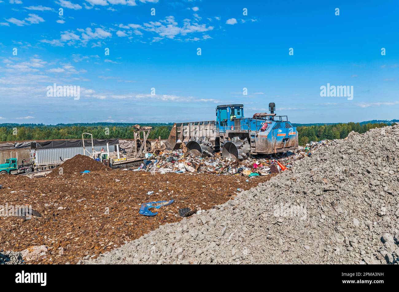 A soil compactor moving around and manipulating trash in the dirt on a ...