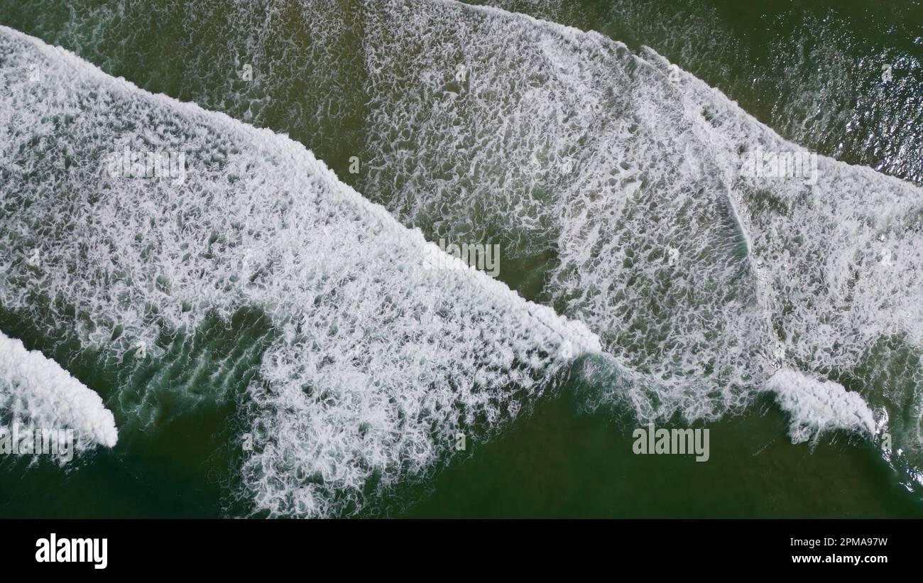 Overhead view of waves crashing on sandy beach aerial - a bird's eye ...