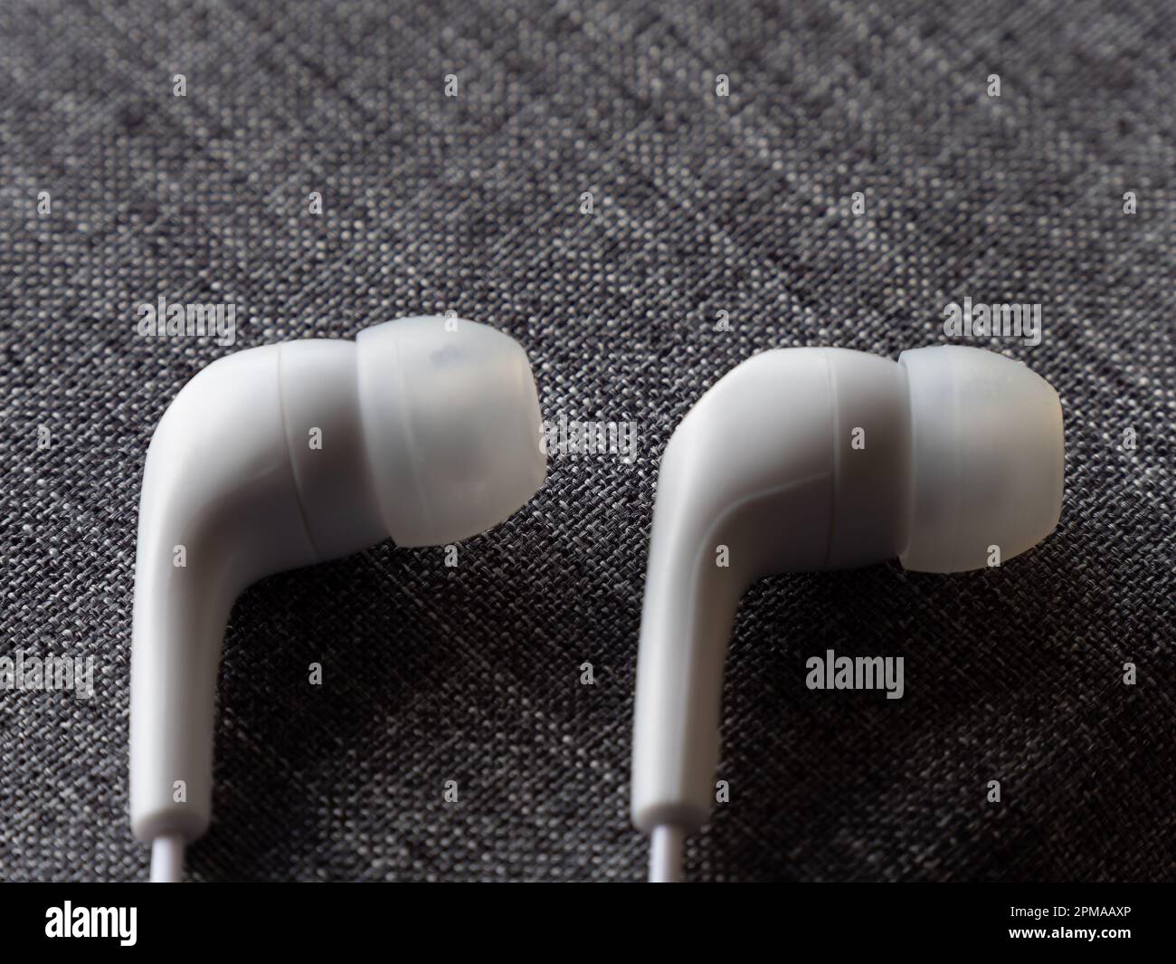 Two wired headphones on a gray background, a close-up shot. White ...