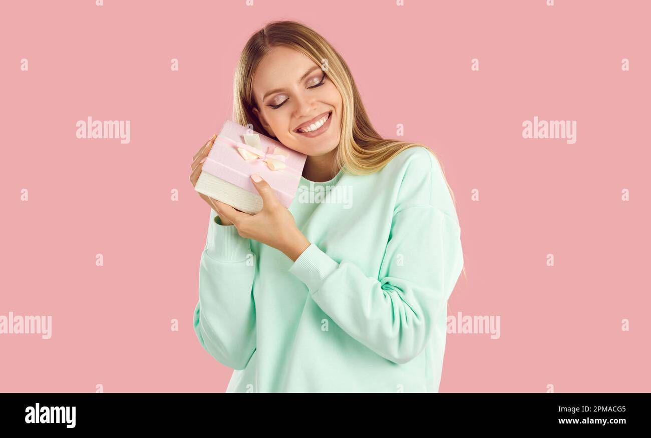 Happy young woman hugging gift box with delicate pink bow Stock Photo ...