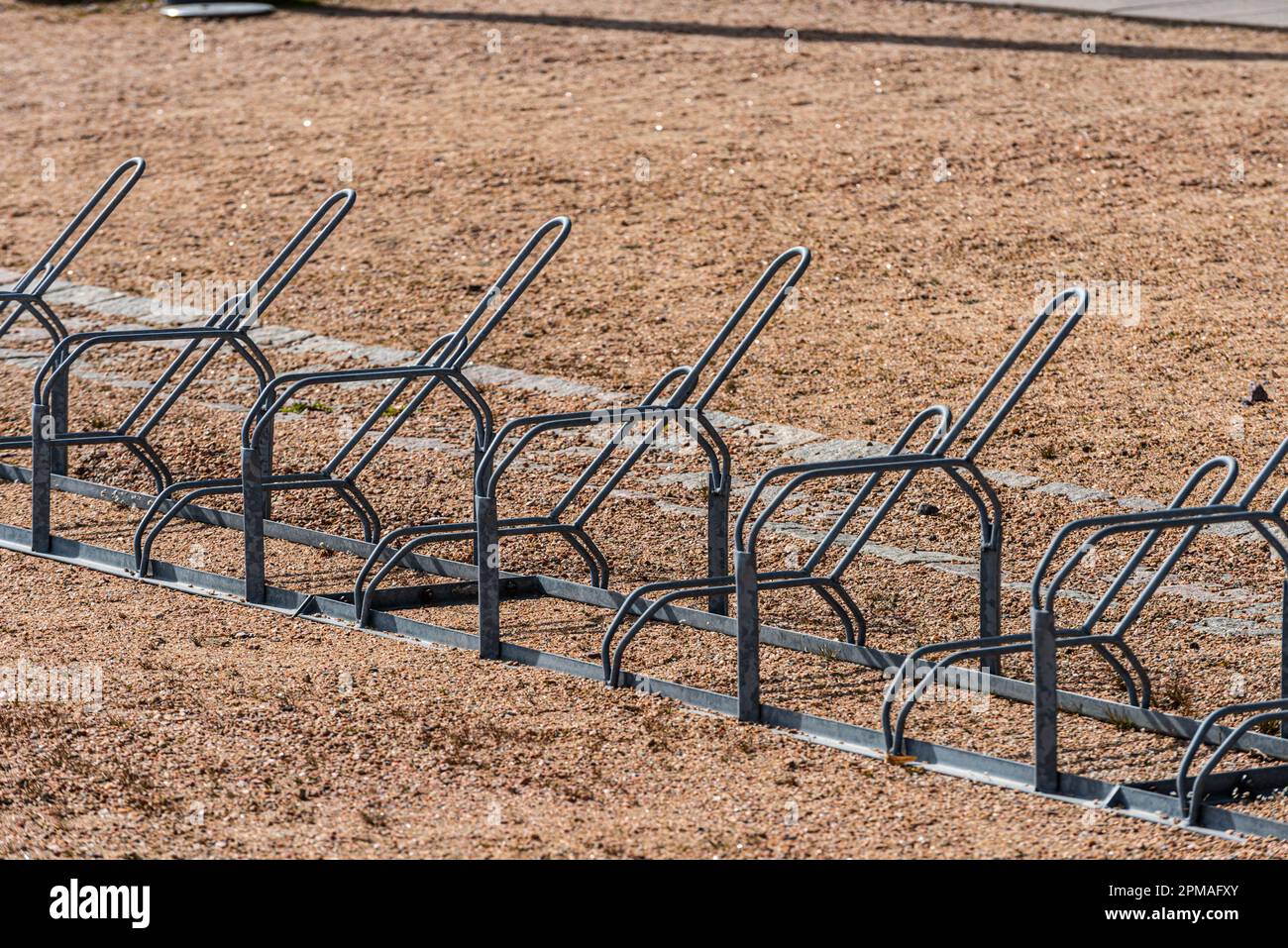 Row of bicycle racks on gravel ground Stock Photo - Alamy