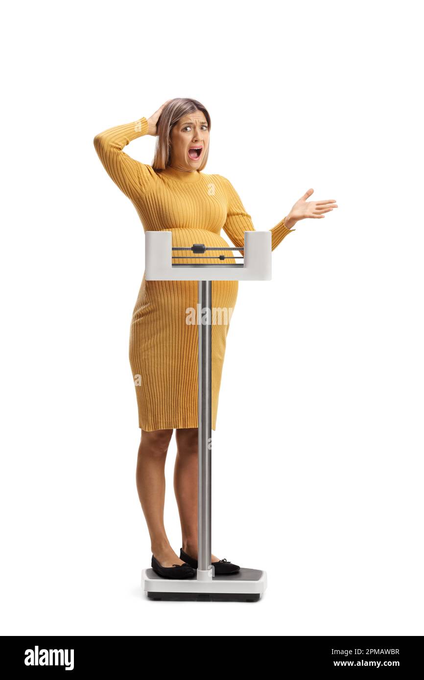 Shocked pregnant woman standing on a weight scale and holding her head ...