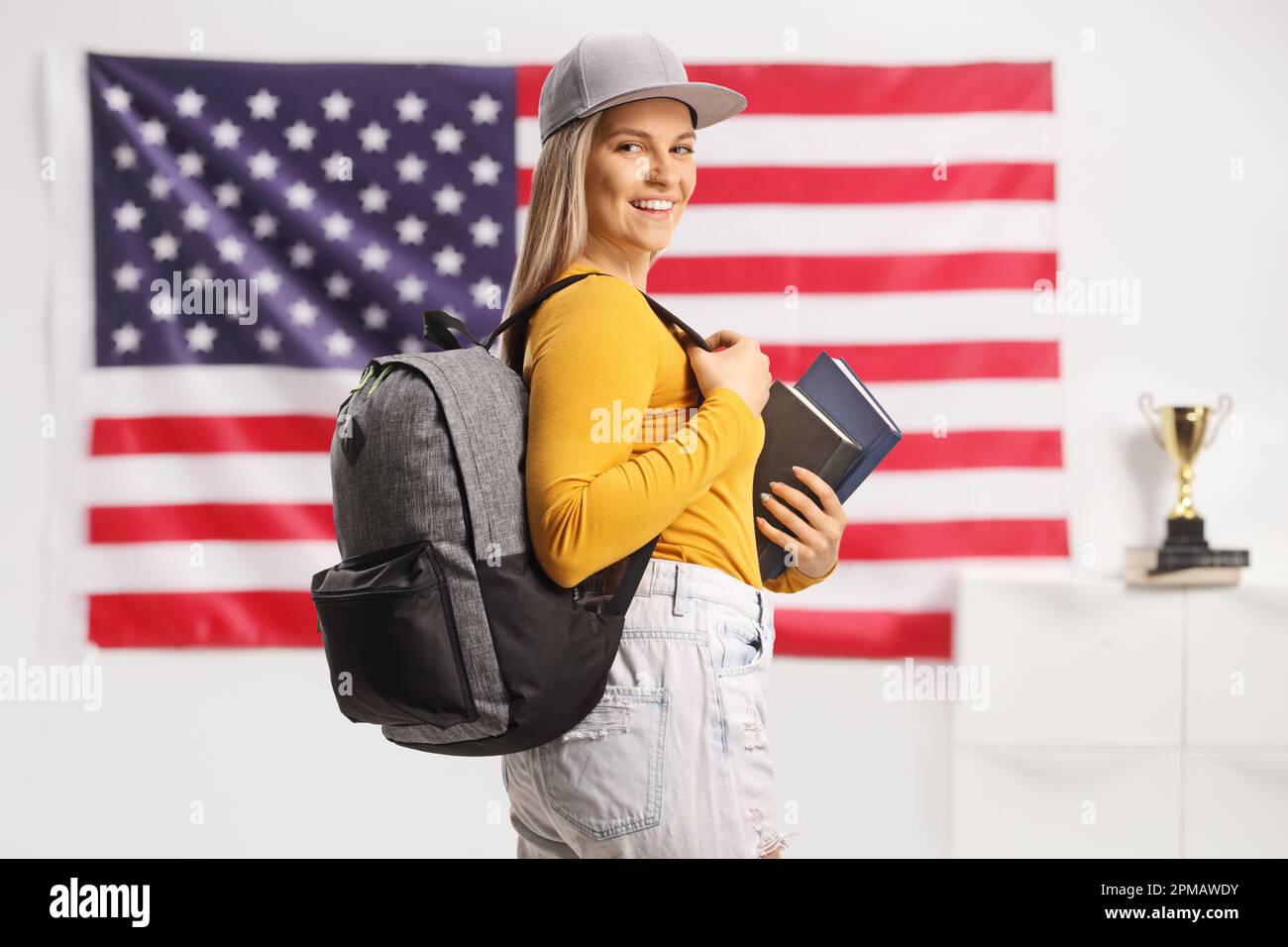 Female student with a backpack looking over shoulder and holding books ...