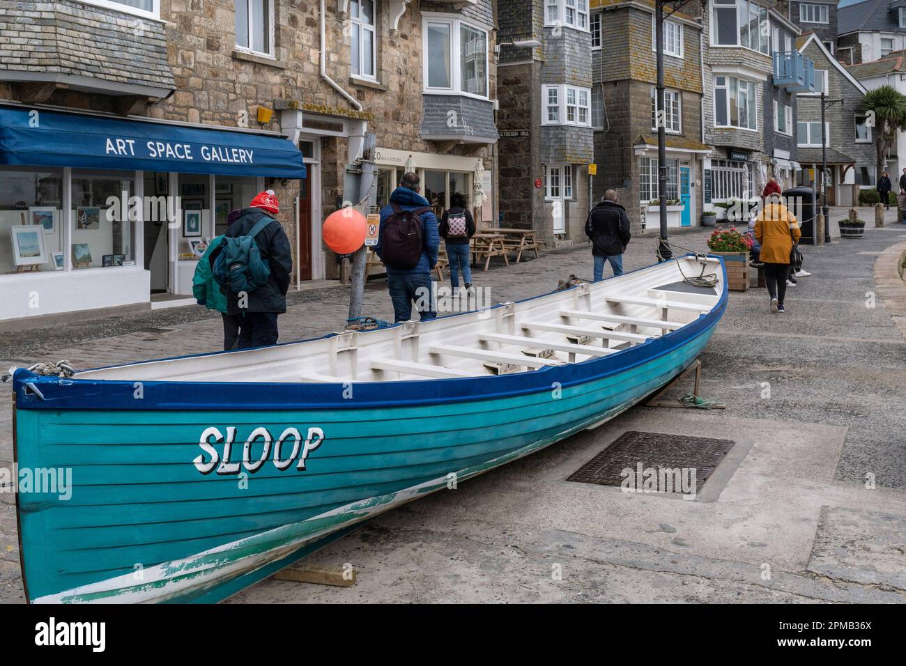 Visitors walking along Wharf Road past a traditional Pilot Gig called ...