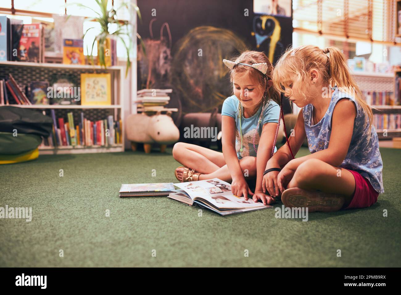 Two primary schoolgirls doing homework in school library. Students ...