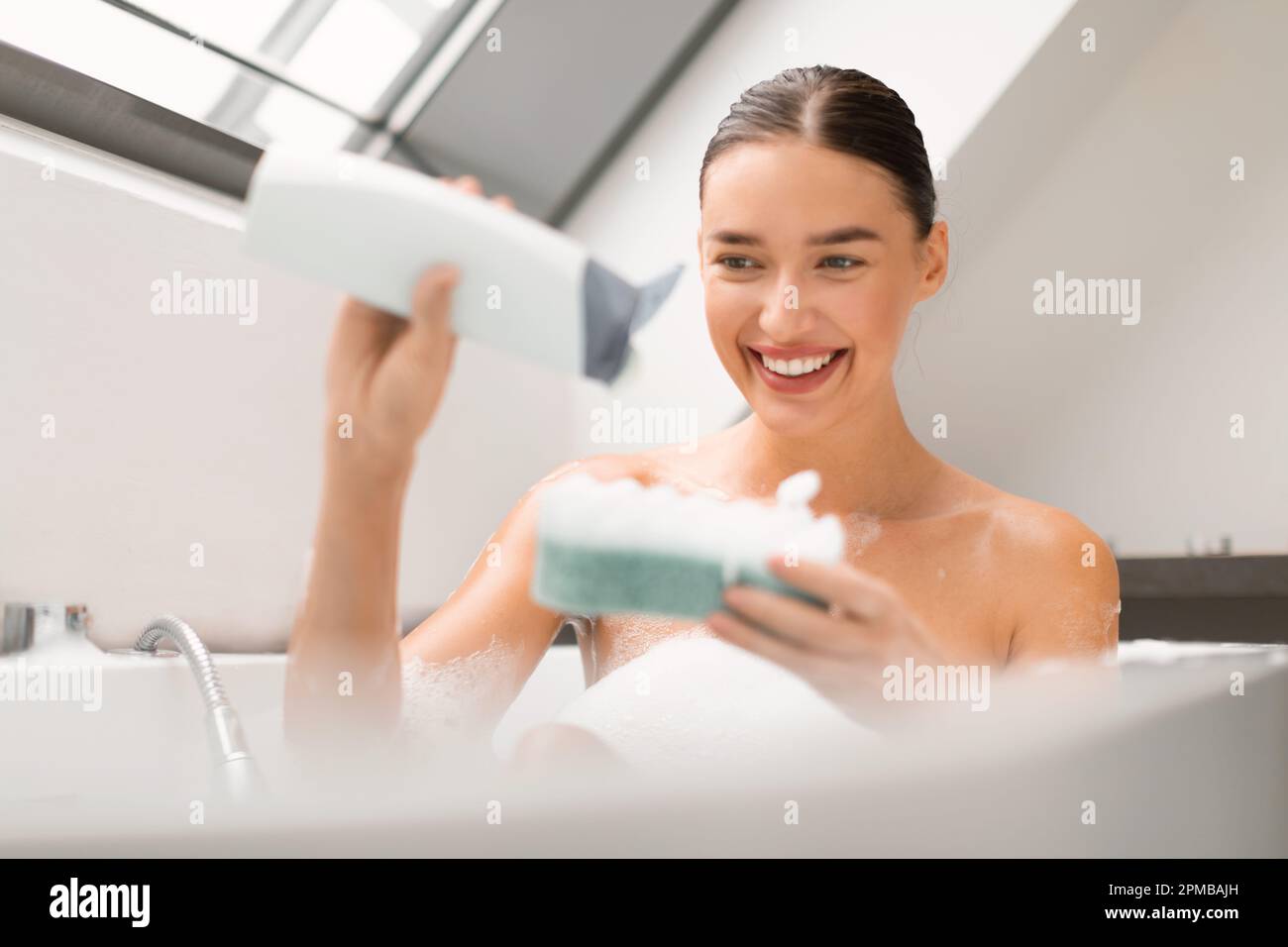 Female Taking Bath Squeezing Shower Gel On Sponge In Bathroom Stock ...