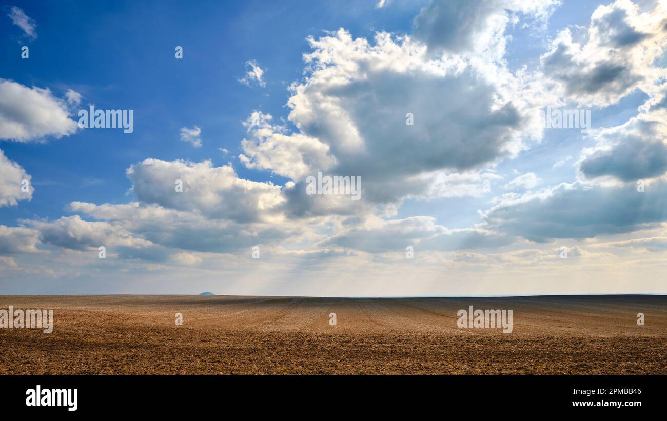 Dry brown soil on a plowed agricultural field under blue sky with ...